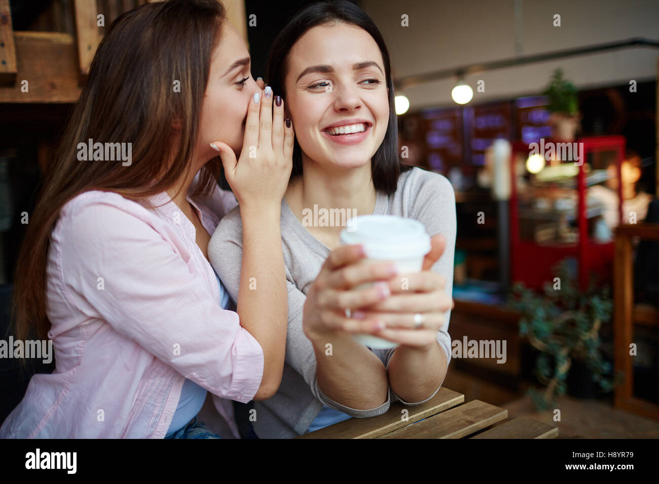 Cheerful girls gossiping while having drink in cafe Stock Photo - Alamy