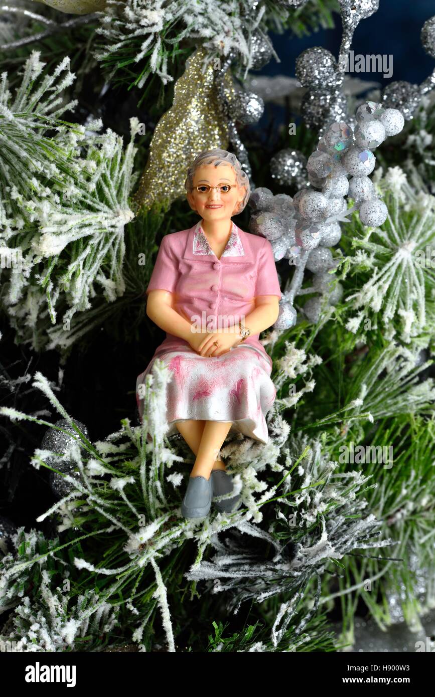 An elderly senior figurine woman sitting on the branches of a christmas ...