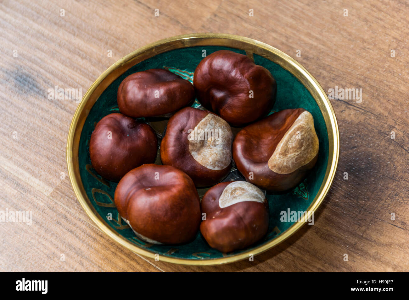 Small green pot of chestnuts lying on wooden floor Stock Photo - Alamy
