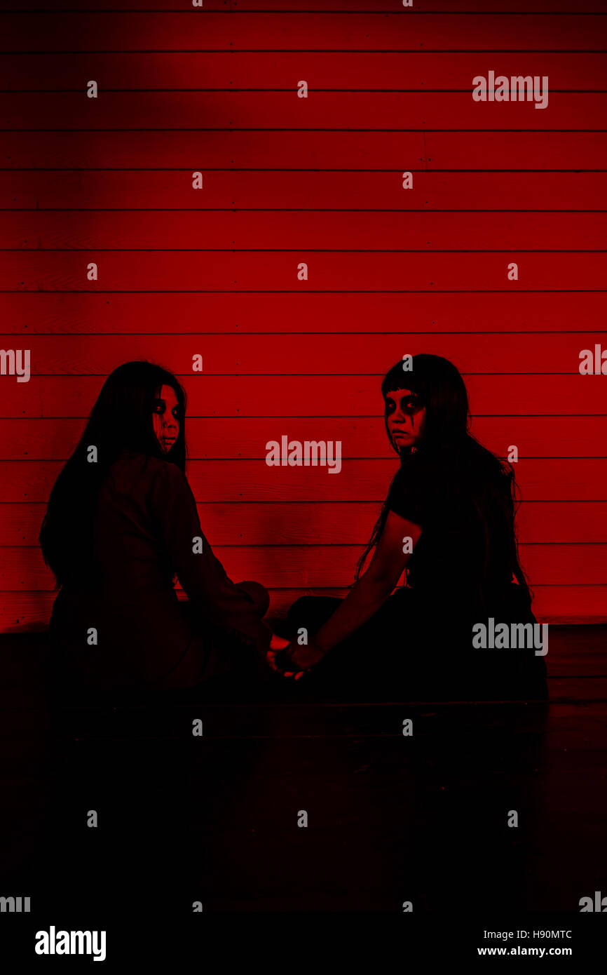 Girls sitting in front of the wall and looking back to the cameras ...