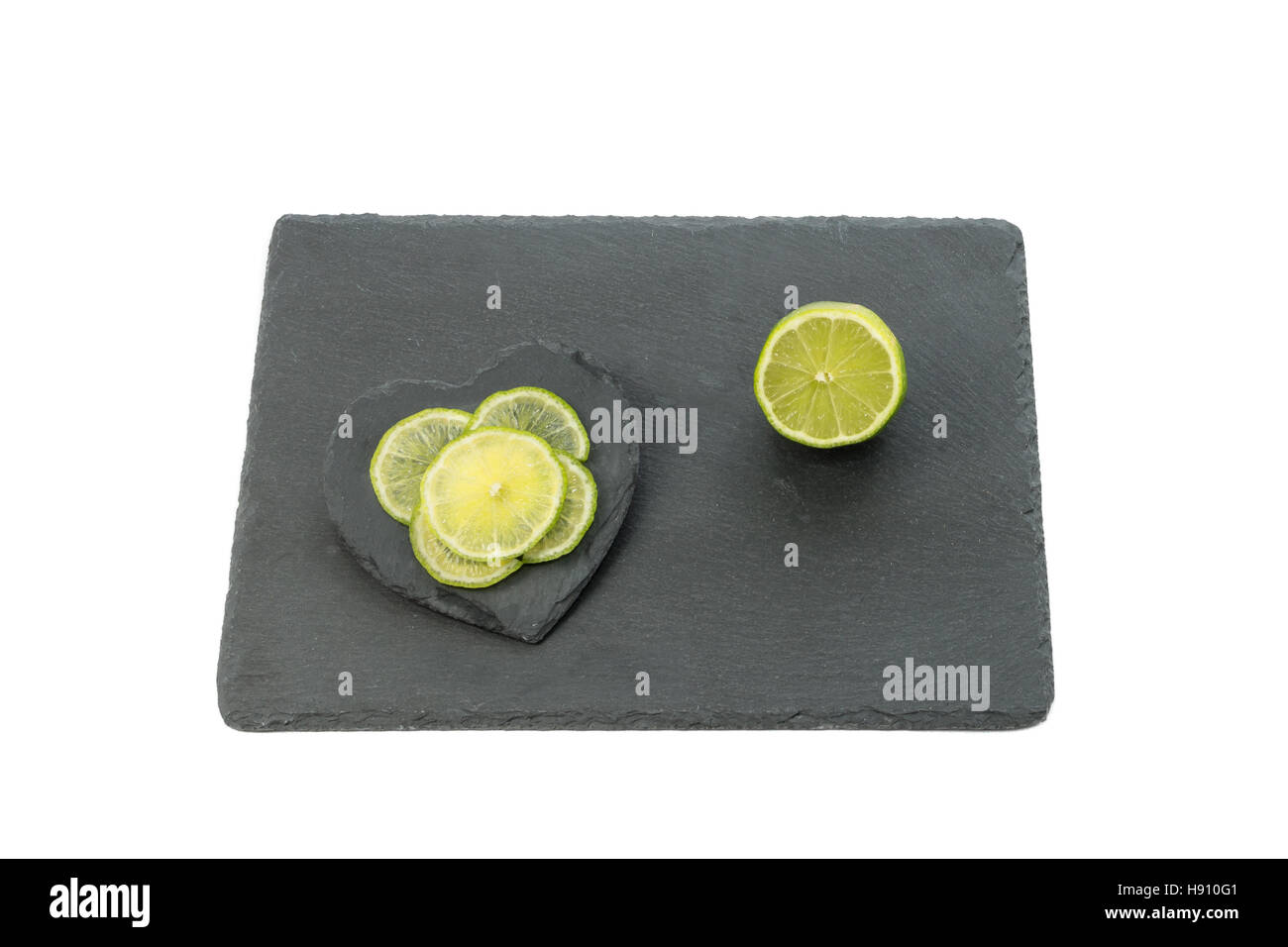 Lime slices and half lime on black slate board isolated on white ...