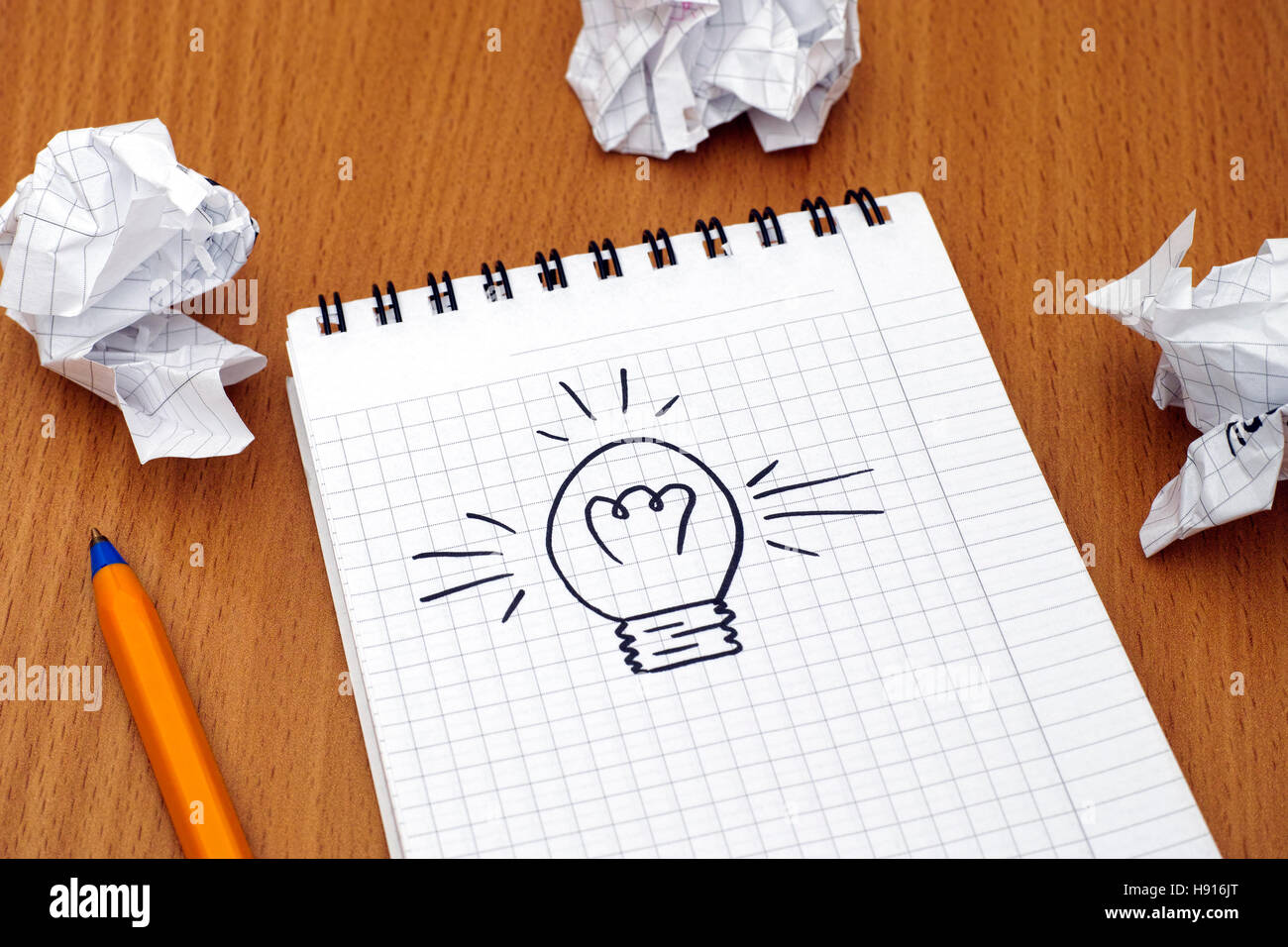 Light bulb drawn on white note pad with ballpoint pen and crumpled ...