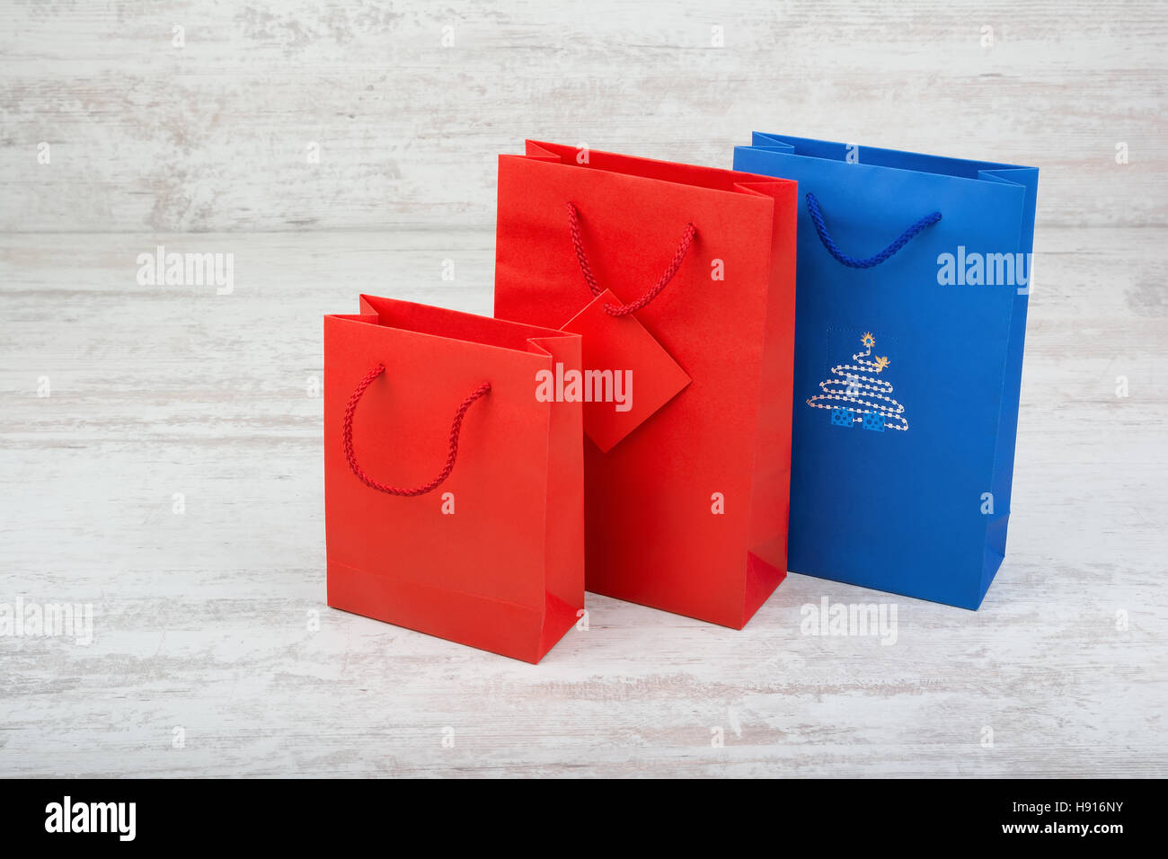 Red and blue gift bags on a white wooden background Stock Photo - Alamy