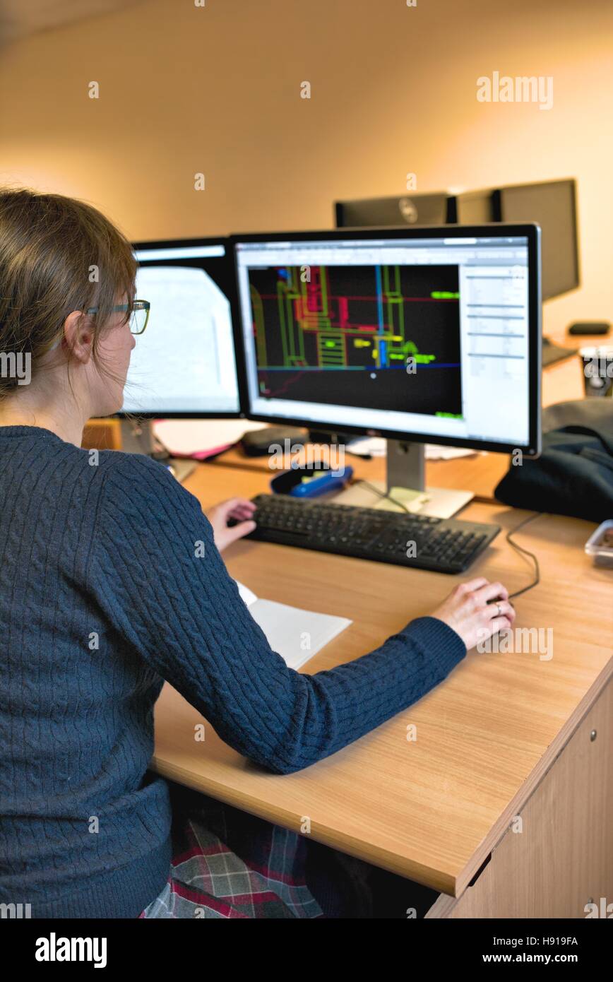 Young woman working in office on computer. Female architect in glasses ...