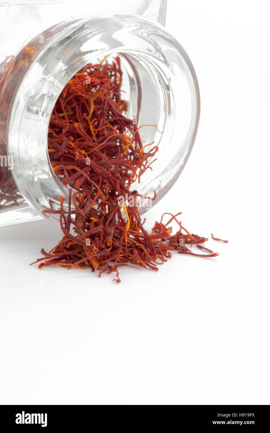 vertical image of saffron coming from a glass jar with a white ...