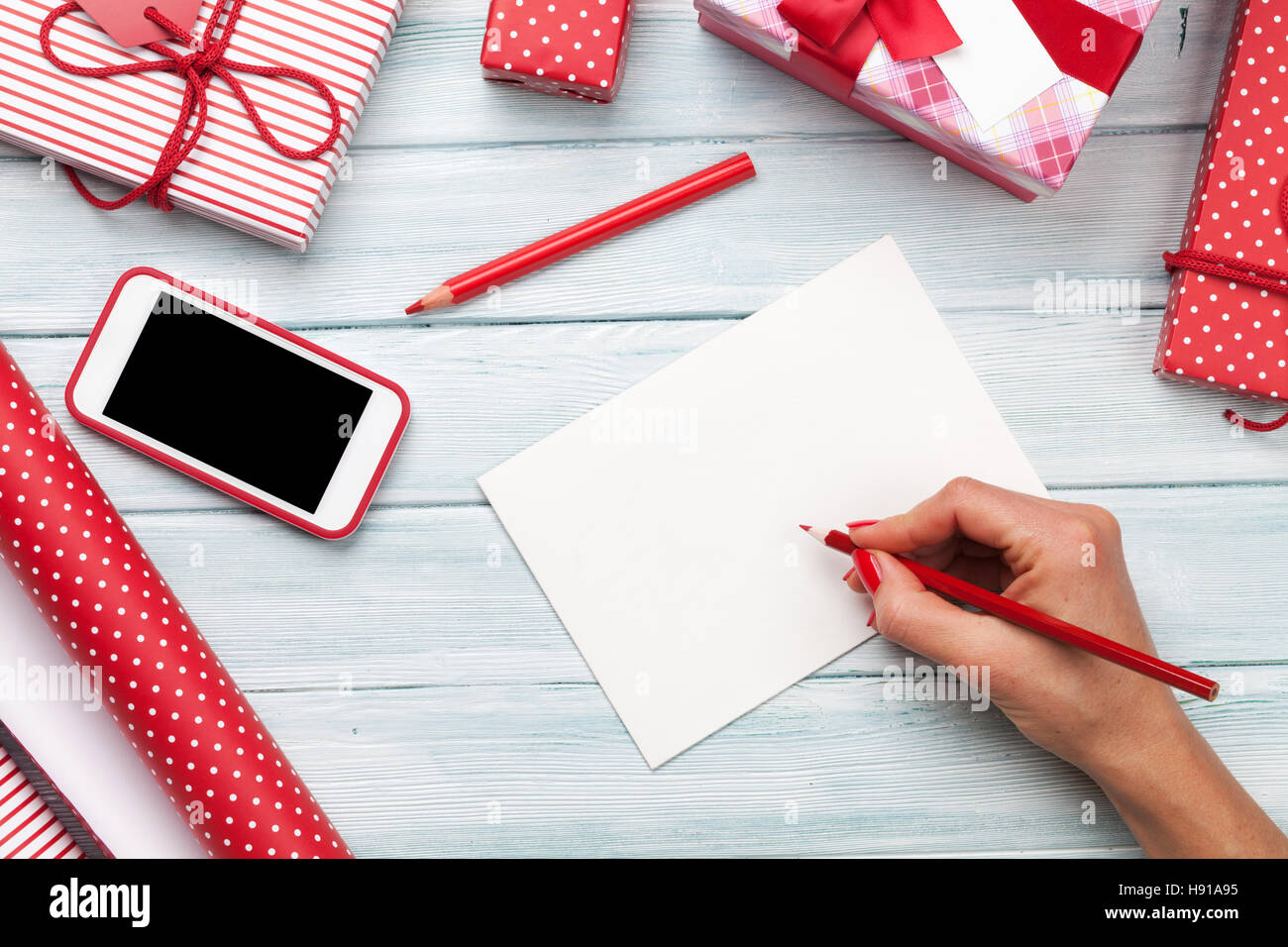 Female writing greeting card and wrapping christmas gifts. Top view ...