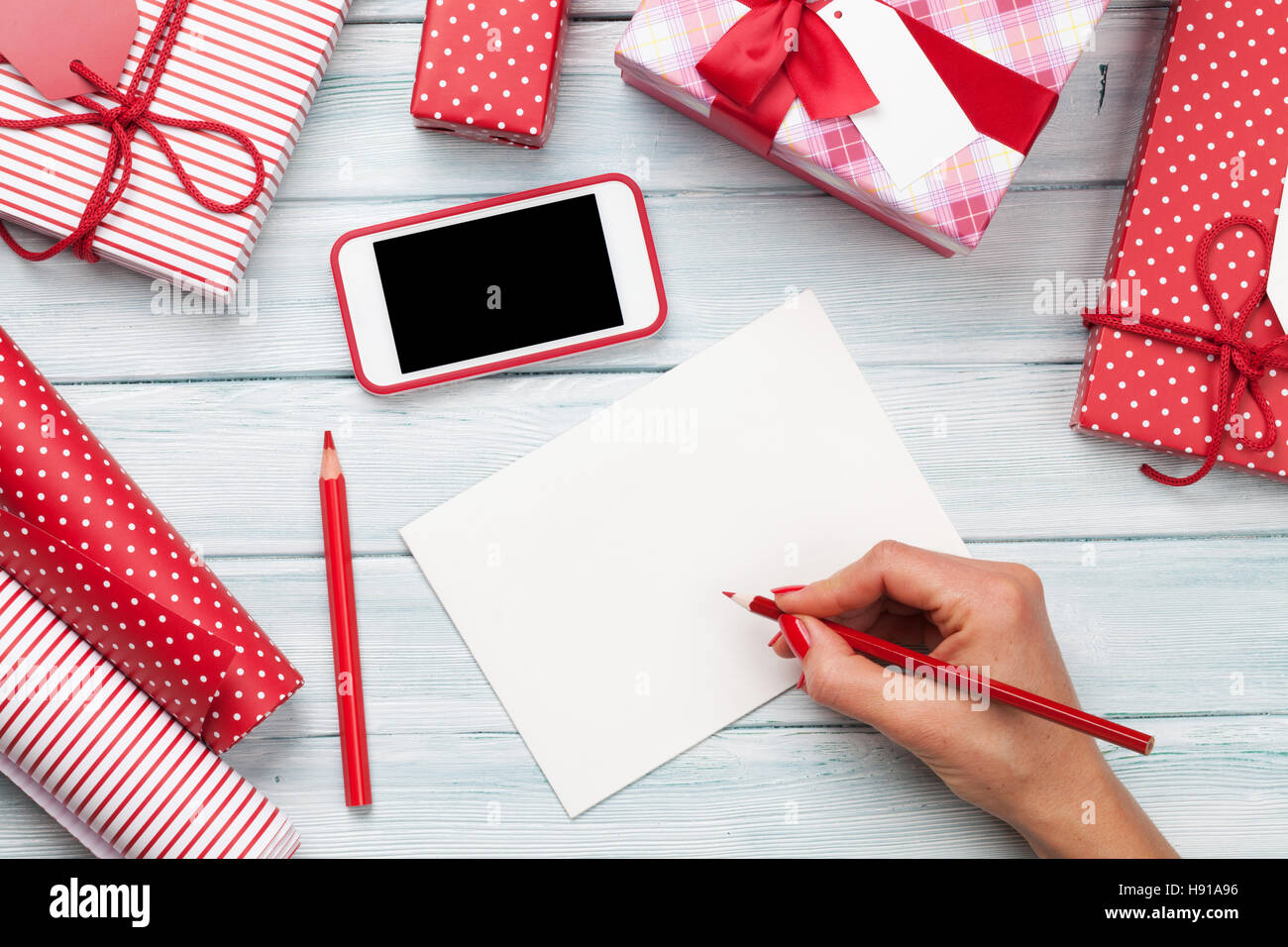 Female writing greeting card and wrapping christmas gifts. Top view ...
