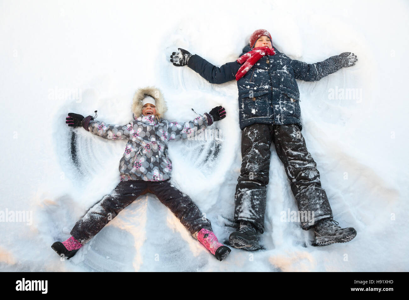 Happy boy and girl having fun together laying in a snow making snow ...