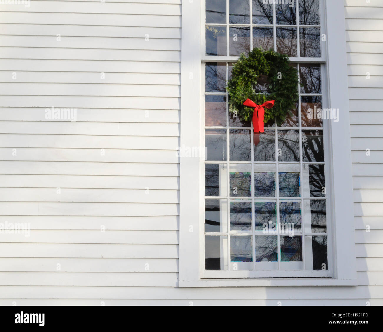 White clapboard building with evergreen wreath and red bow on tall ...