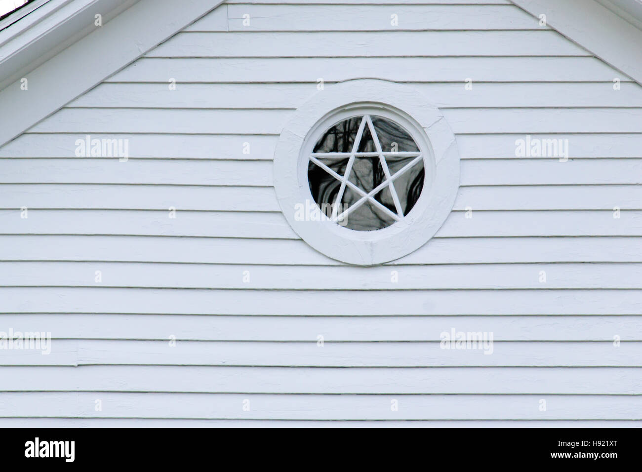 Round window in white clapboard building with star shaped panes Stock ...
