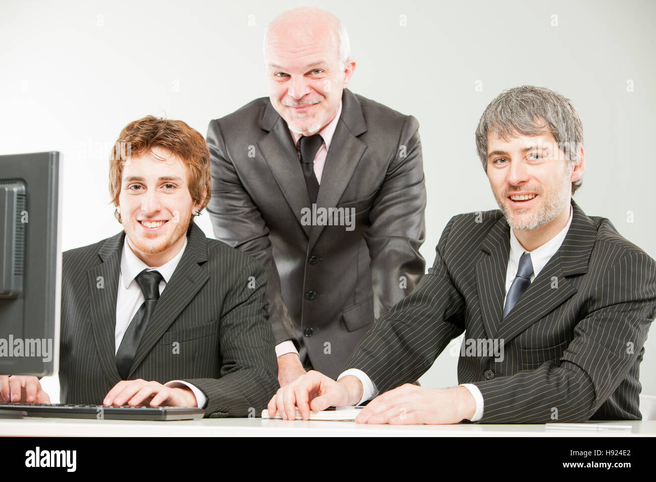 portrait of three businessmen at a desk smiling to you Stock Photo - Alamy