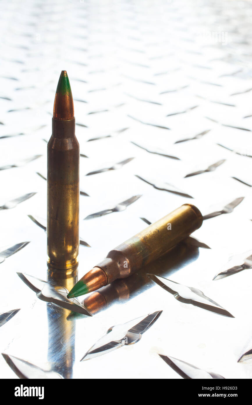 Rifle cartridges with green tipped bullets on a shiny piece of armor ...