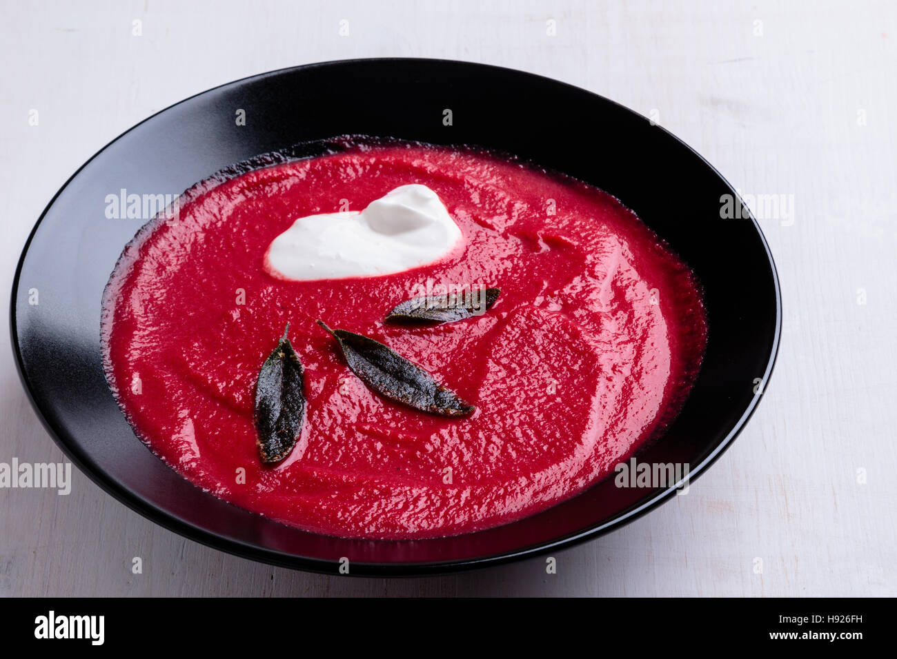 beetroot cream soup in black bowl on white table Stock Photo - Alamy