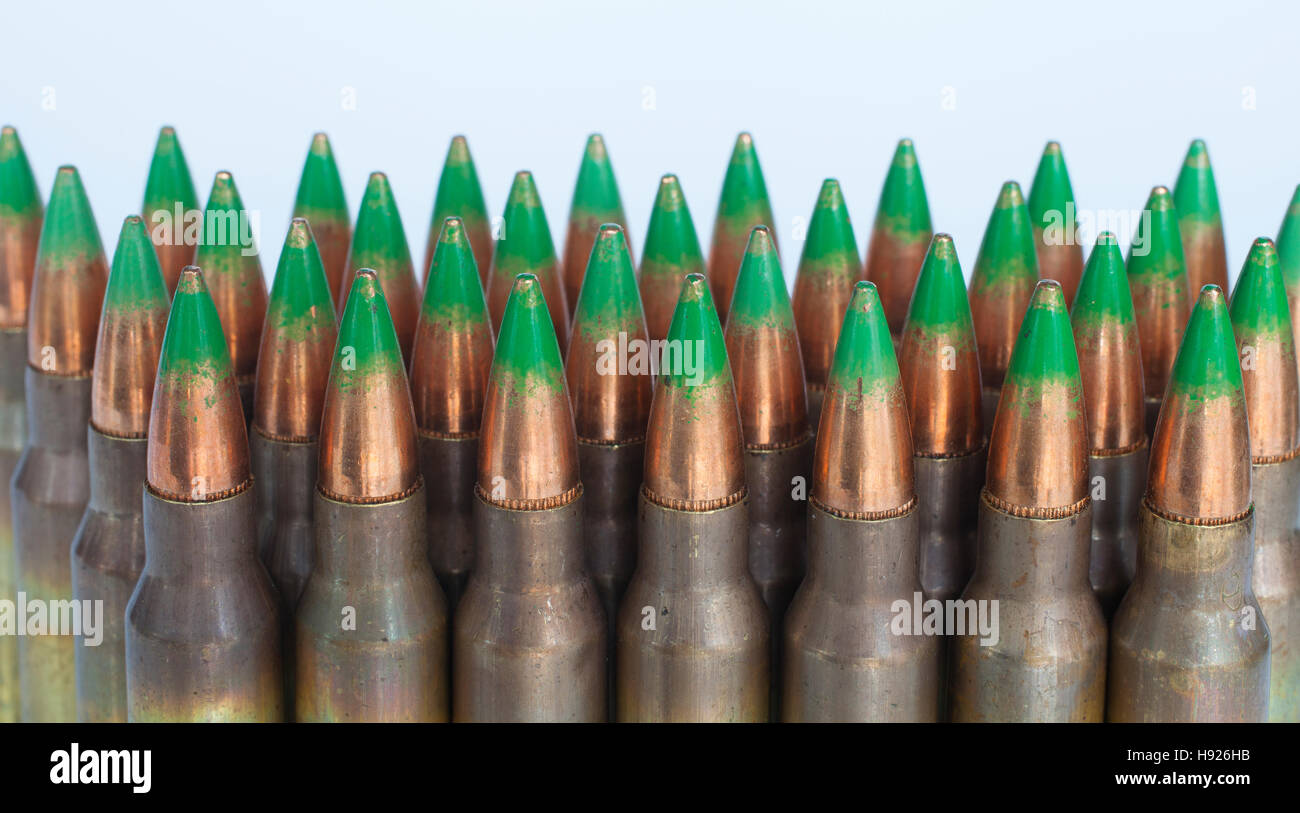 Rifle cartridges with bullets that have a green tip on a white ...