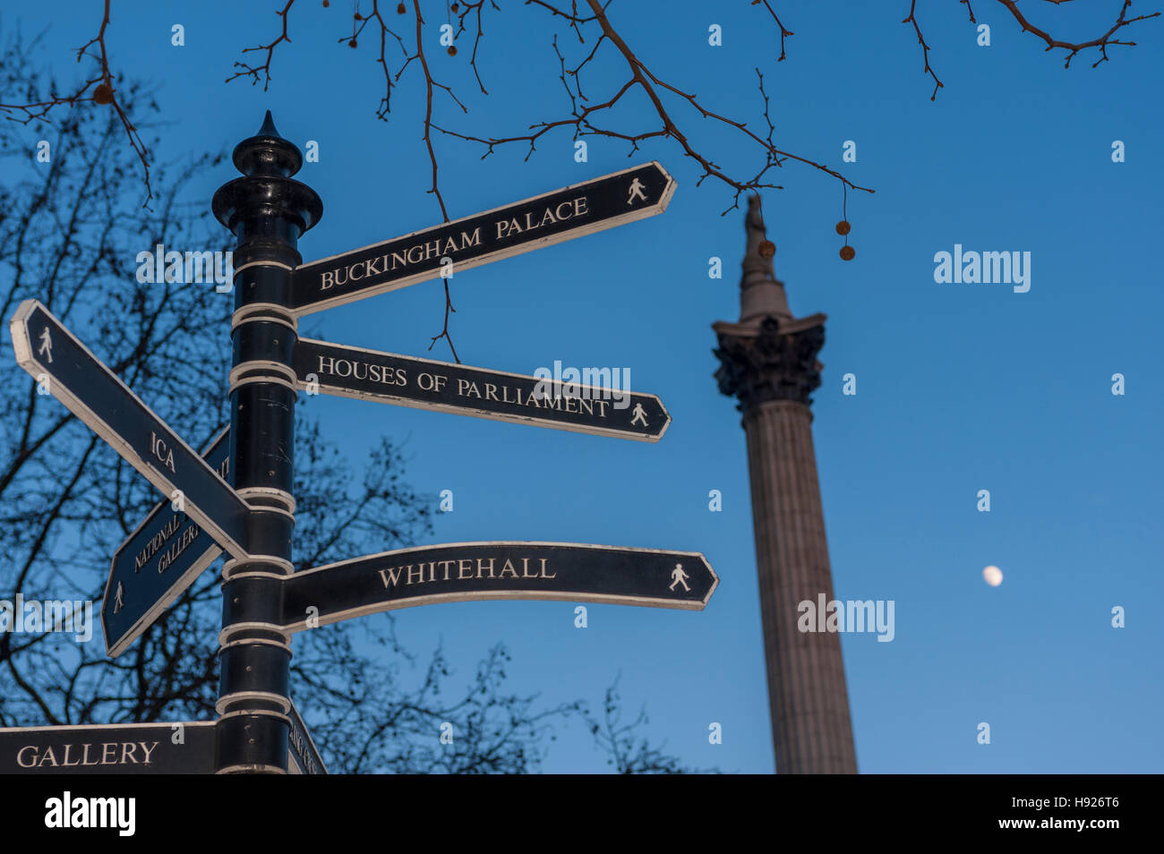 Sign post in trafalgar square at dusk with nelsons coloumn and full ...