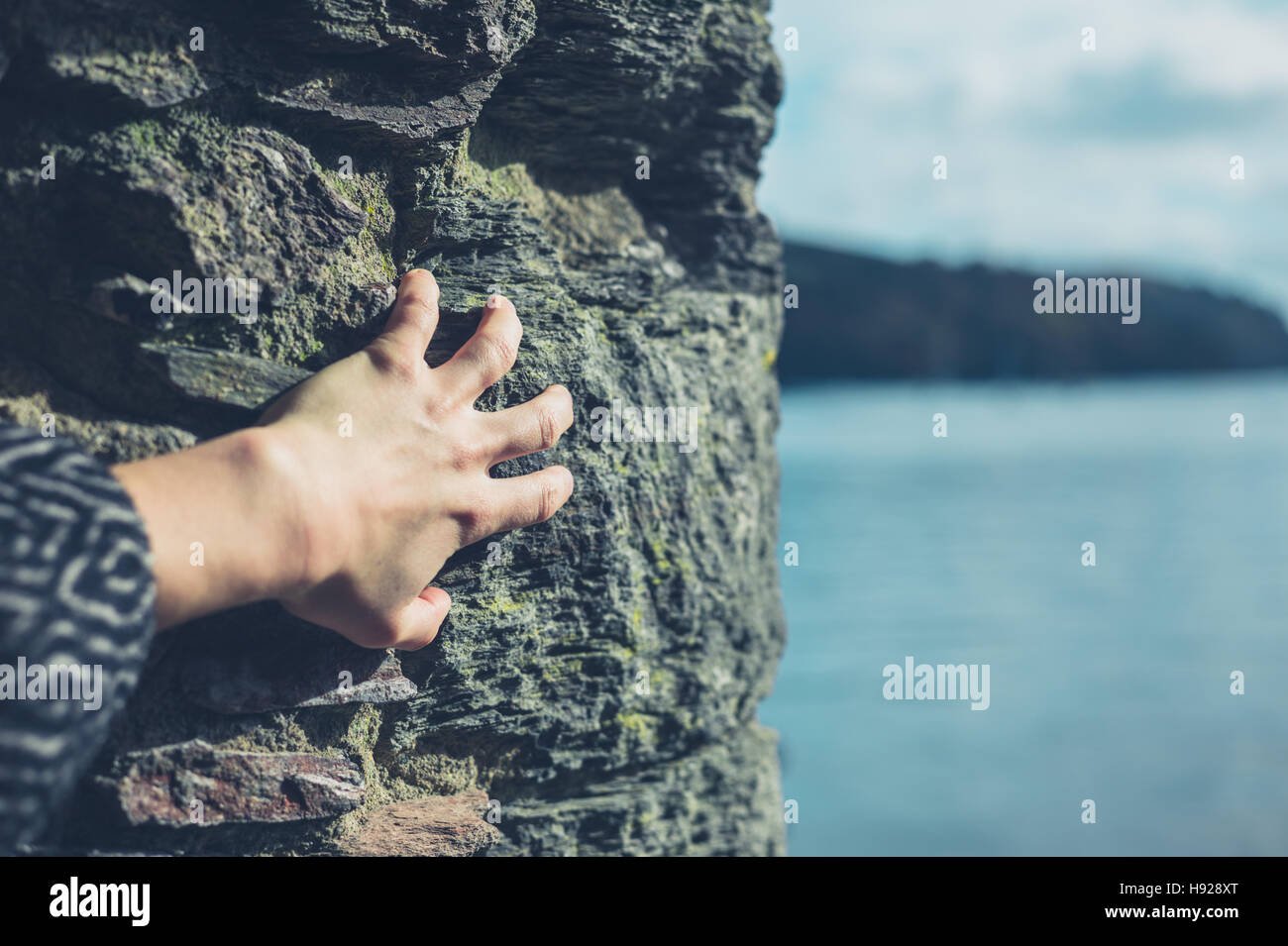 A young female hand is touching a rock wall by the sea Stock Photo - Alamy