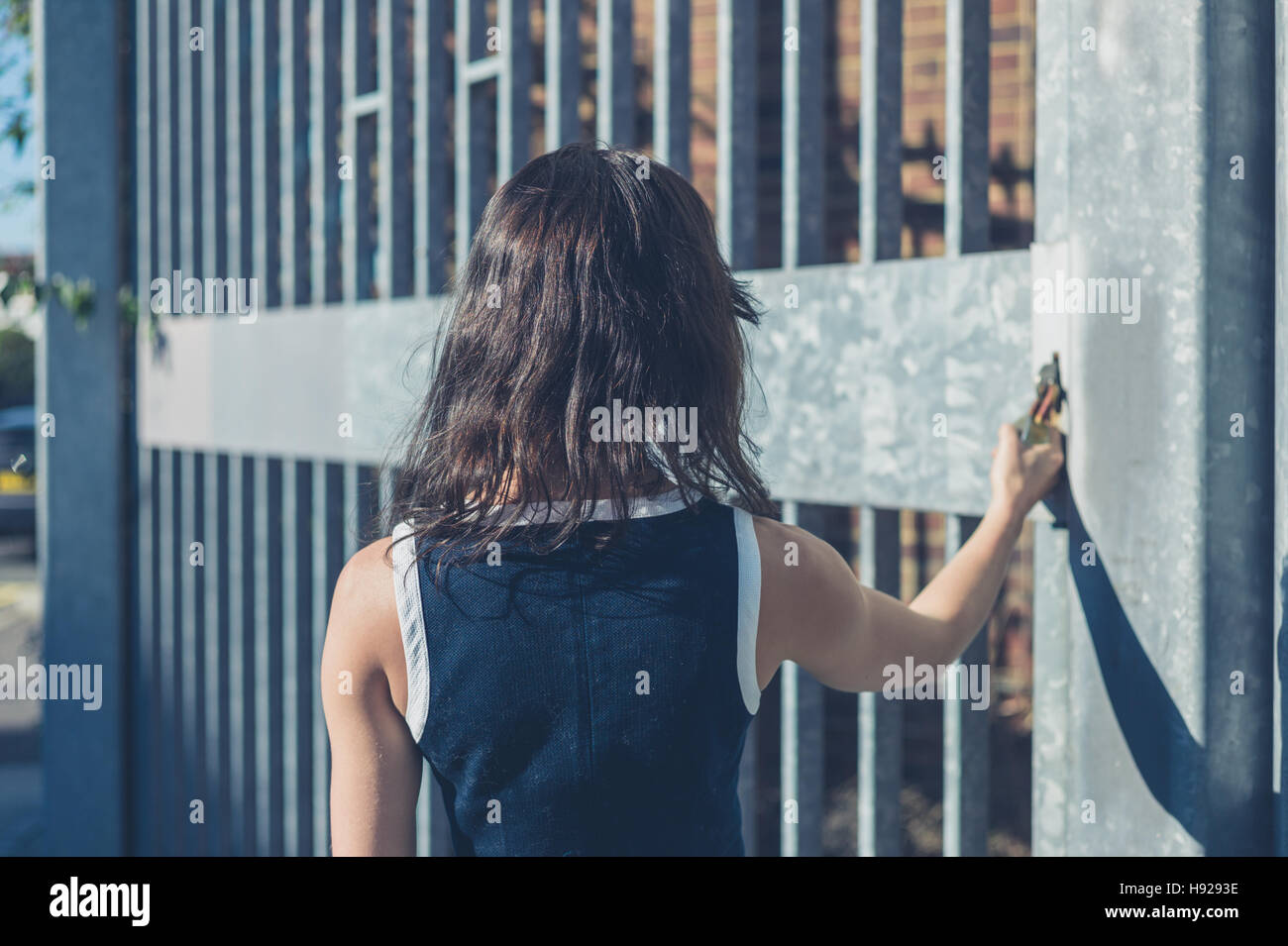 A young woman is grabbing a padlock by a big industrial gate Stock ...