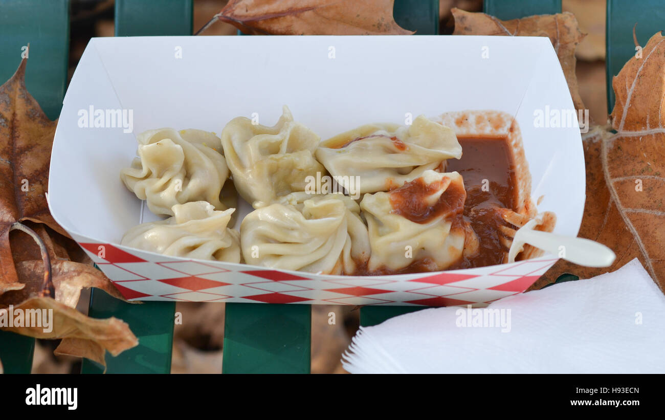 Steamed momos with tomato sauce.- served in a carry-out box at a ...