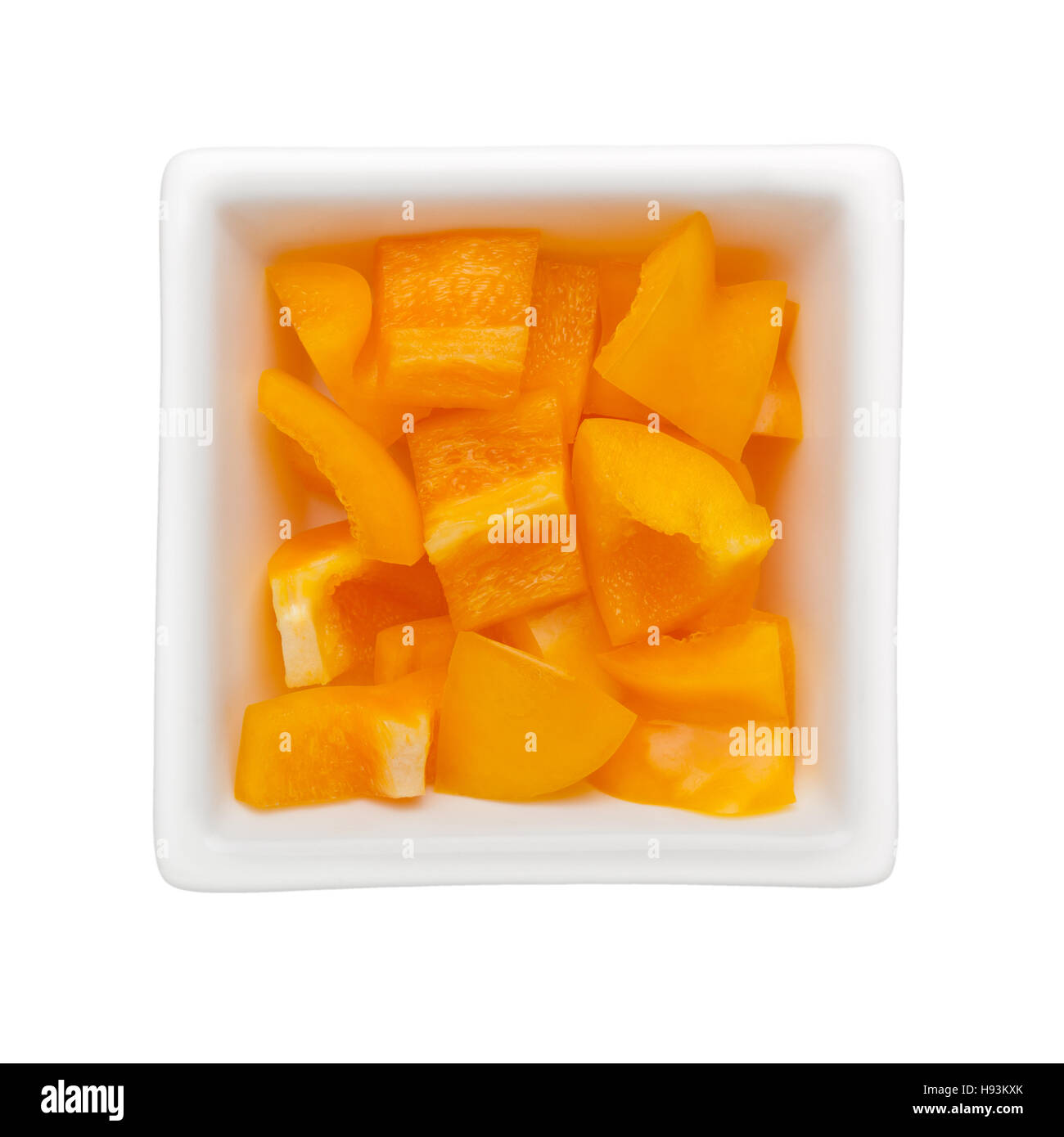 Diced yellow bell pepper in a square bowl isolated on white background ...