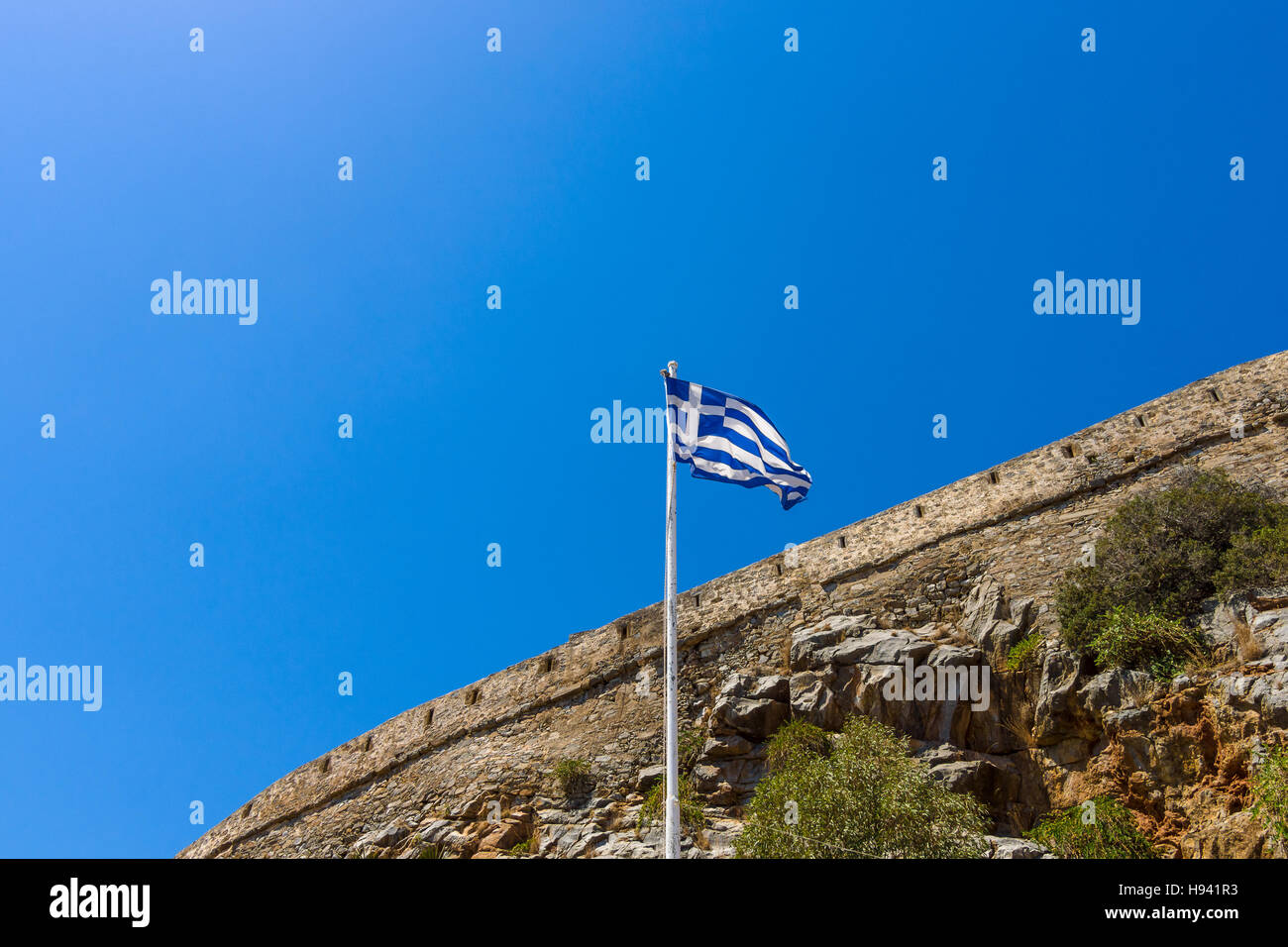 State flag of Greece against the blue sky and the fortress wall Stock ...