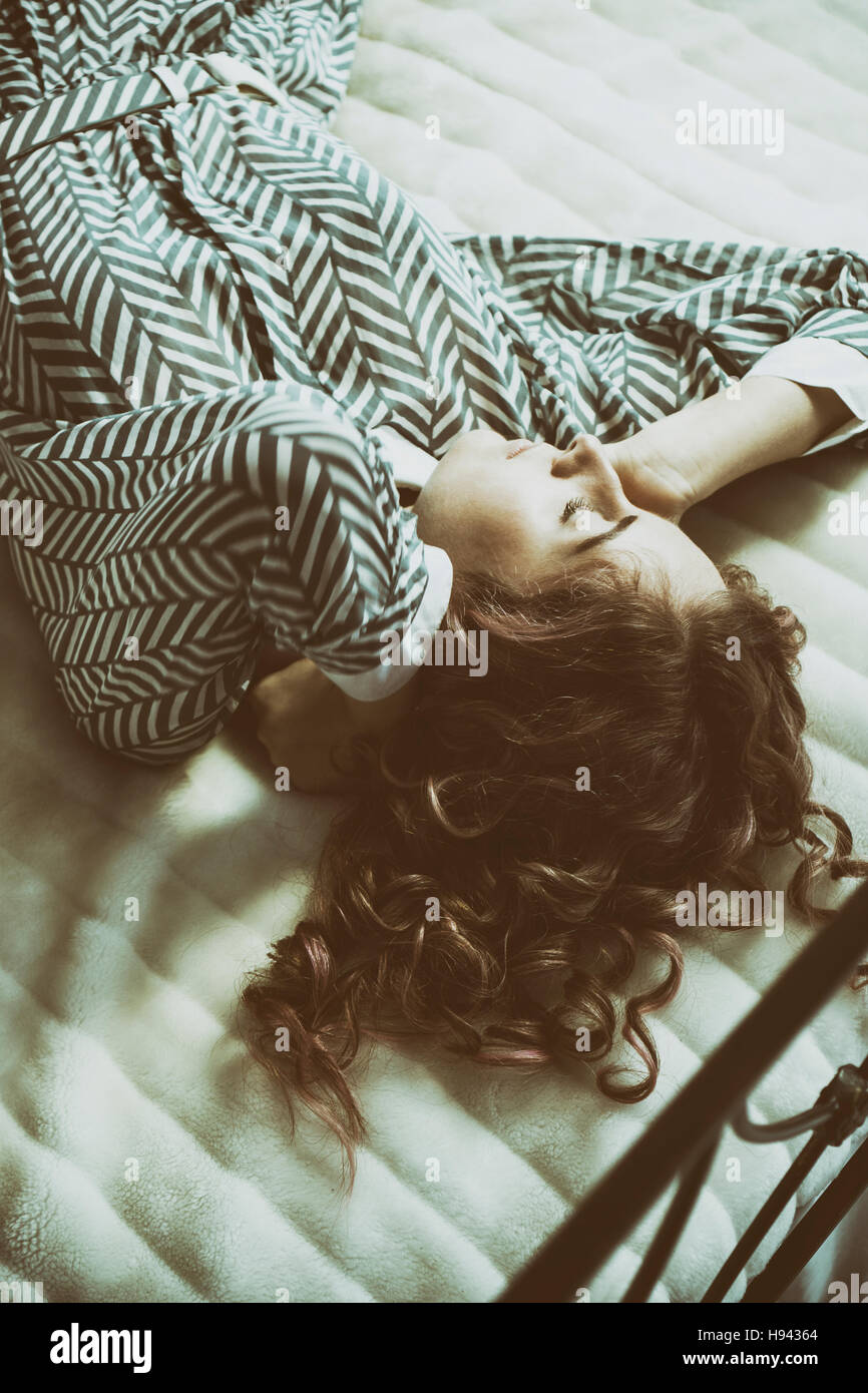 Tired woman laying down in bed Stock Photo - Alamy