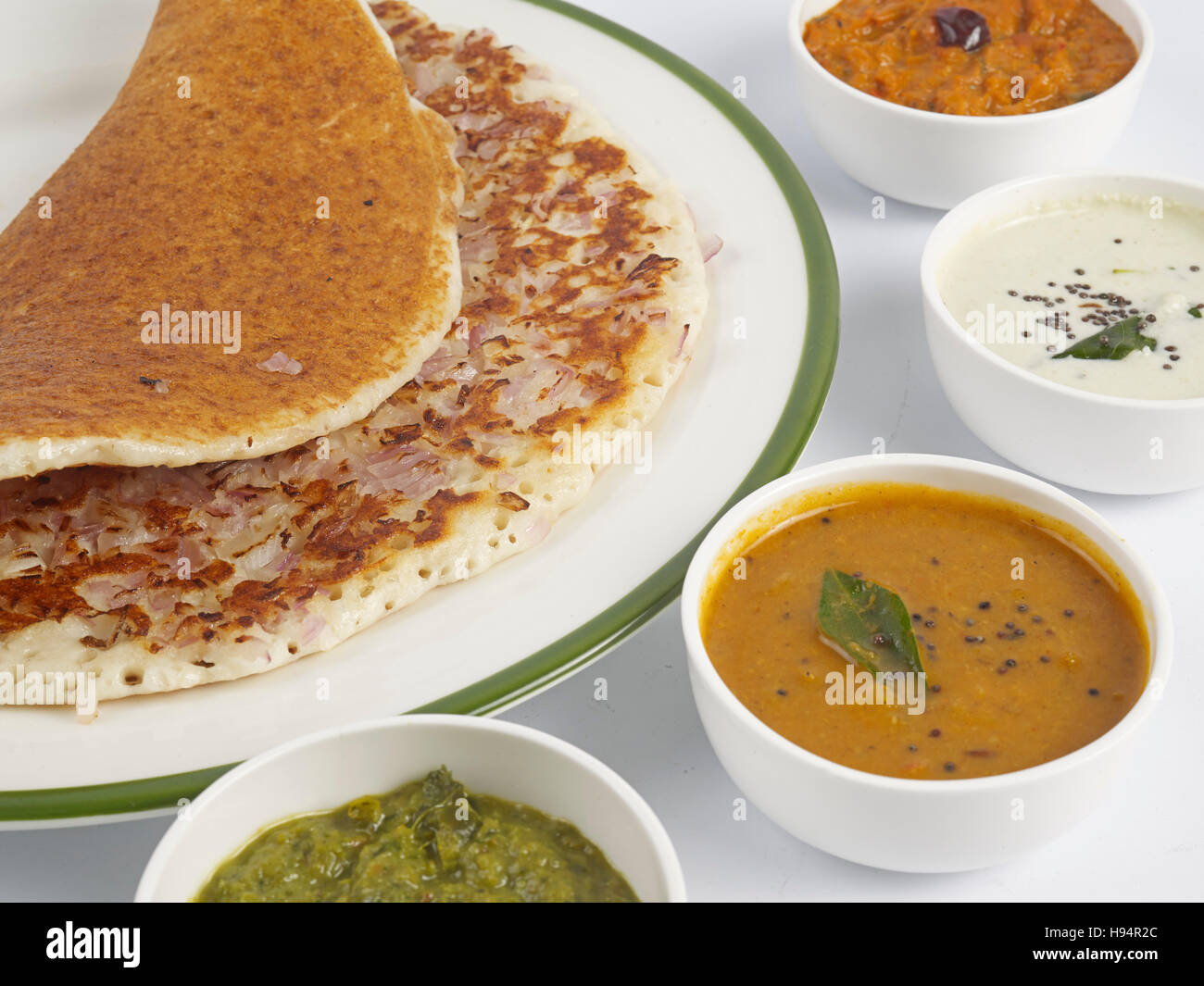 onion uthappam served in a plate with sambar and three types of ...