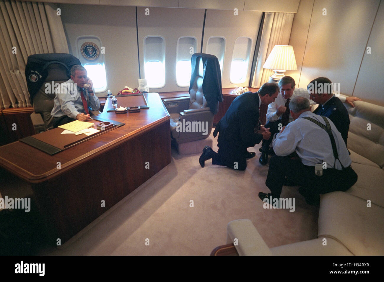 U.S. President George W. Bush talks on the phone as senior staff huddle ...