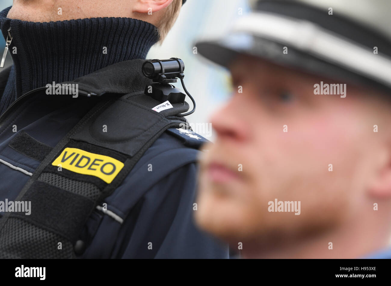 A police officer wearing a video camera on his shoulder in front of a ...