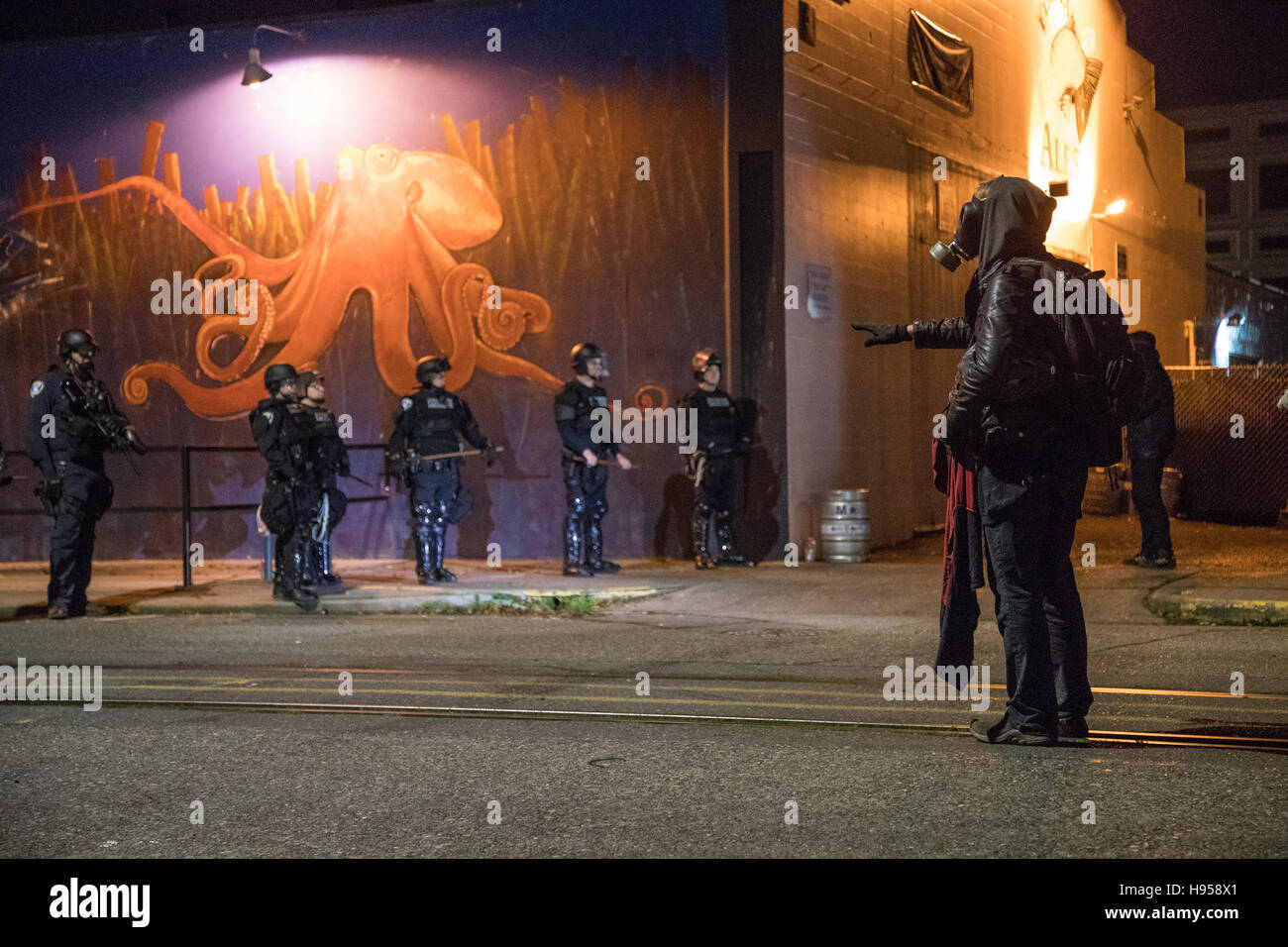A protester wearing a gas mask stands in defiance of a line of riot ...