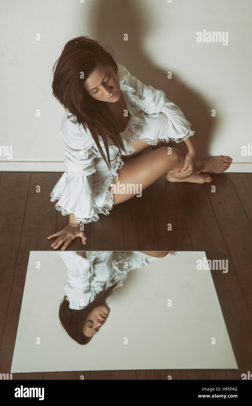 Woman sat on the floor looking at her reflection in the mirror Stock ...