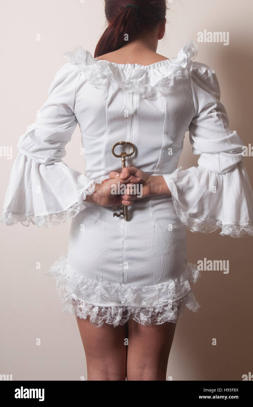 Woman holding a big key behind her back Stock Photo - Alamy