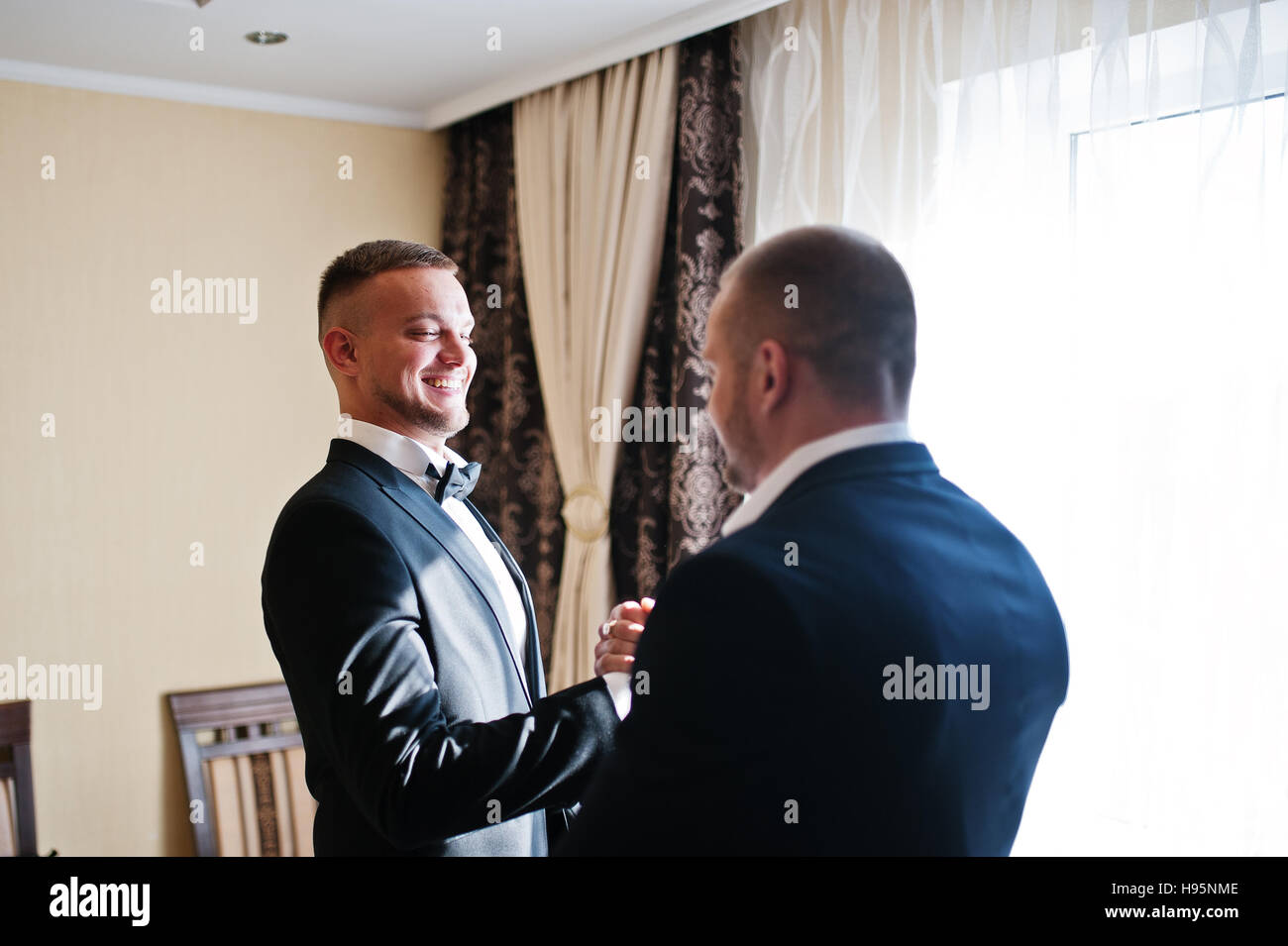 Two handsome male friends meet and shaking hands each other. Groomsman ...