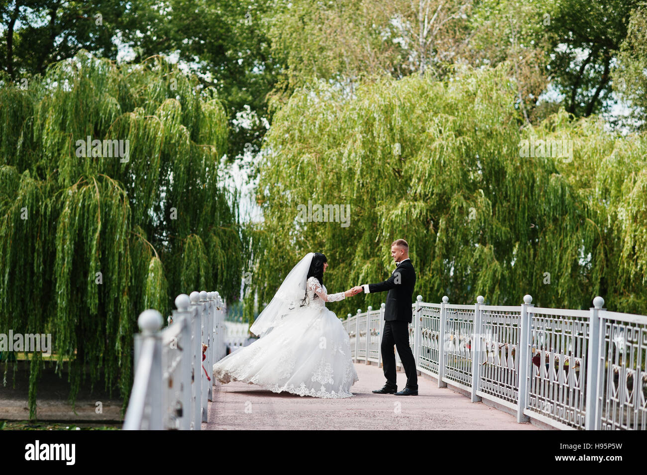 Dancing wedding couple on bridge background island with willow trees ...