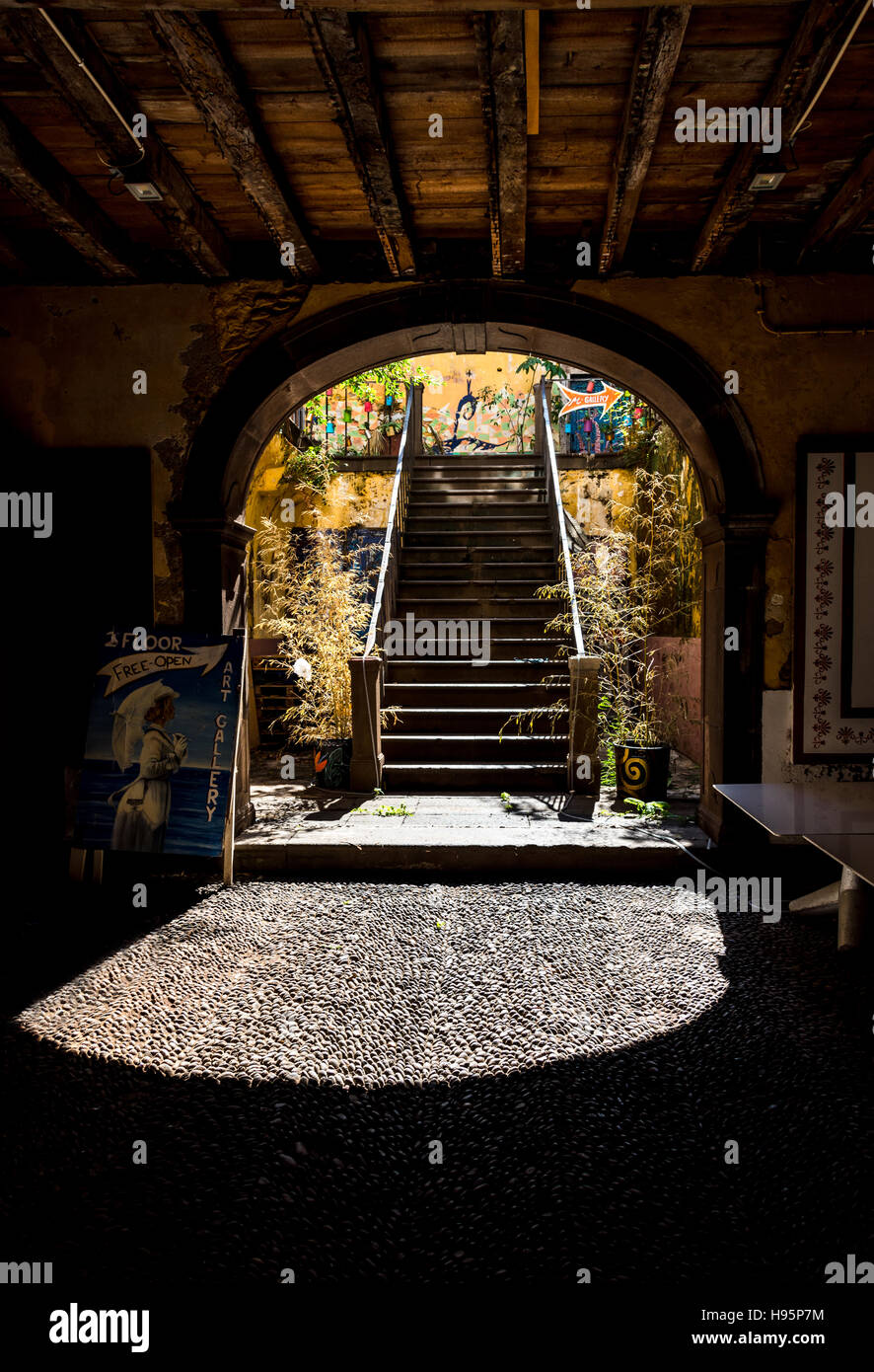 Brightly lit central courtyard with staircase, through dark entrance ...
