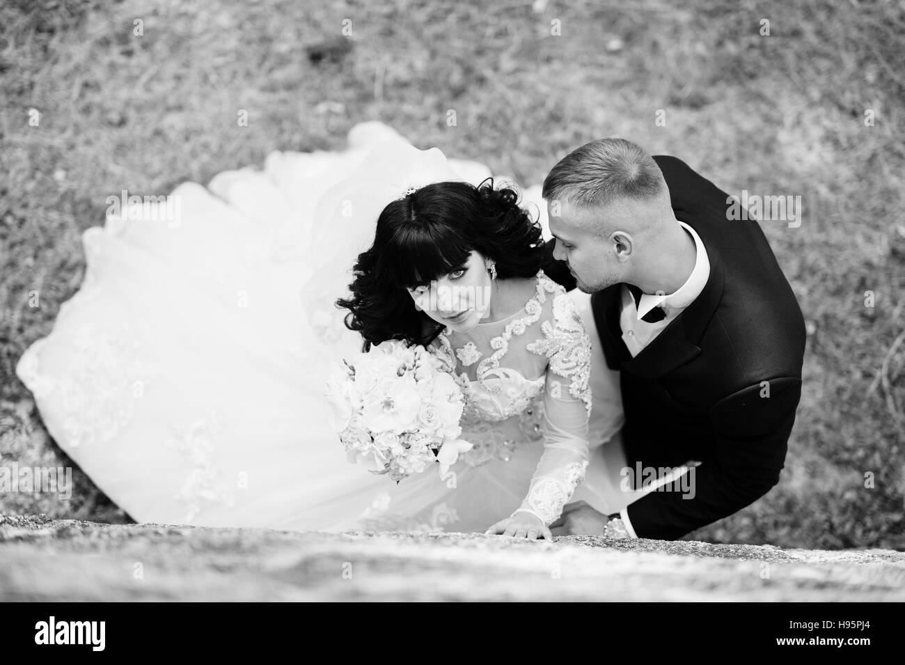 View from above of stylish wedding couple at park. Groom kiss neck of ...