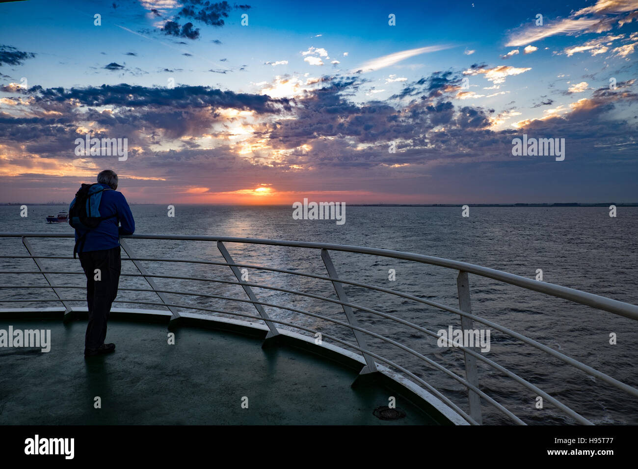Man sailing off into sunset on large ship Stock Photo - Alamy