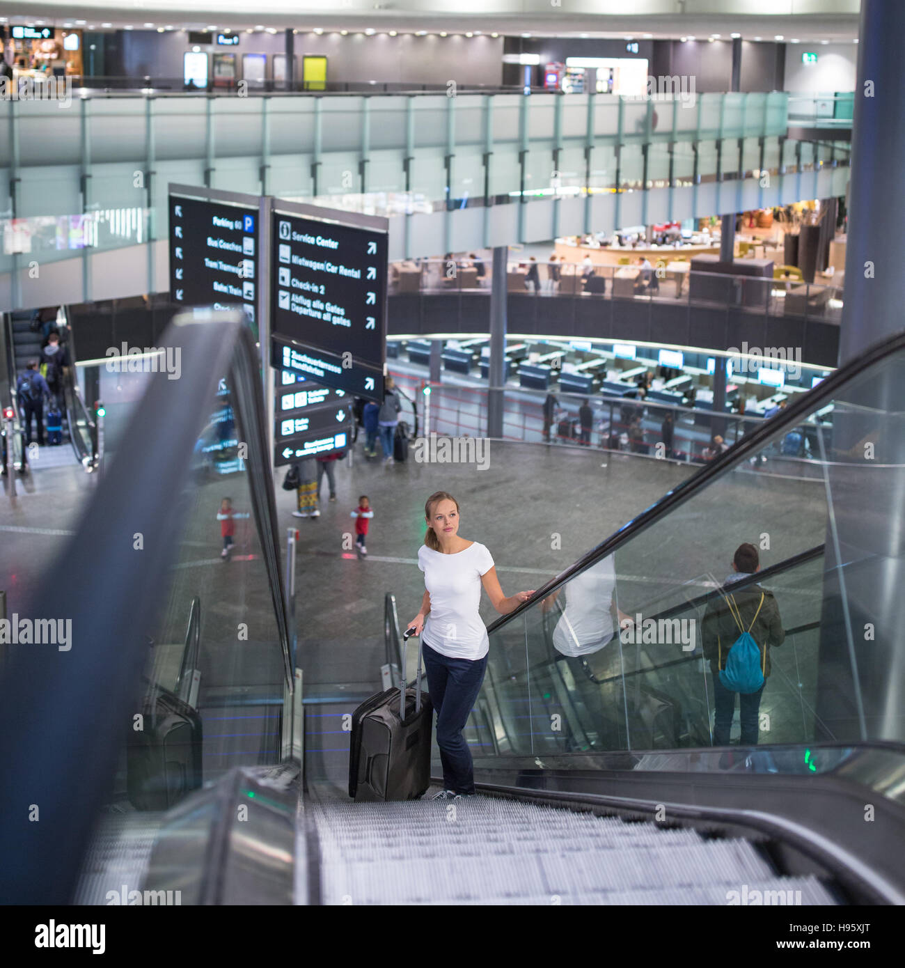 Young female passenger at the airport, using her tablet computer while ...