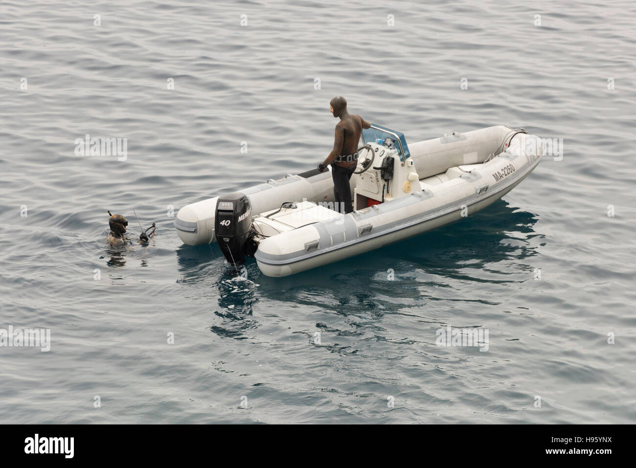 Divers wearing wetsuits in a small rib boat fish for seafood on the ...