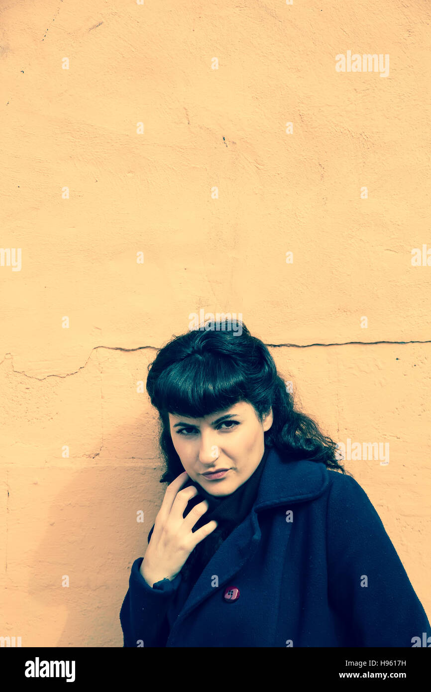 A retro styled girl waiting and leaning against a wall Stock Photo - Alamy