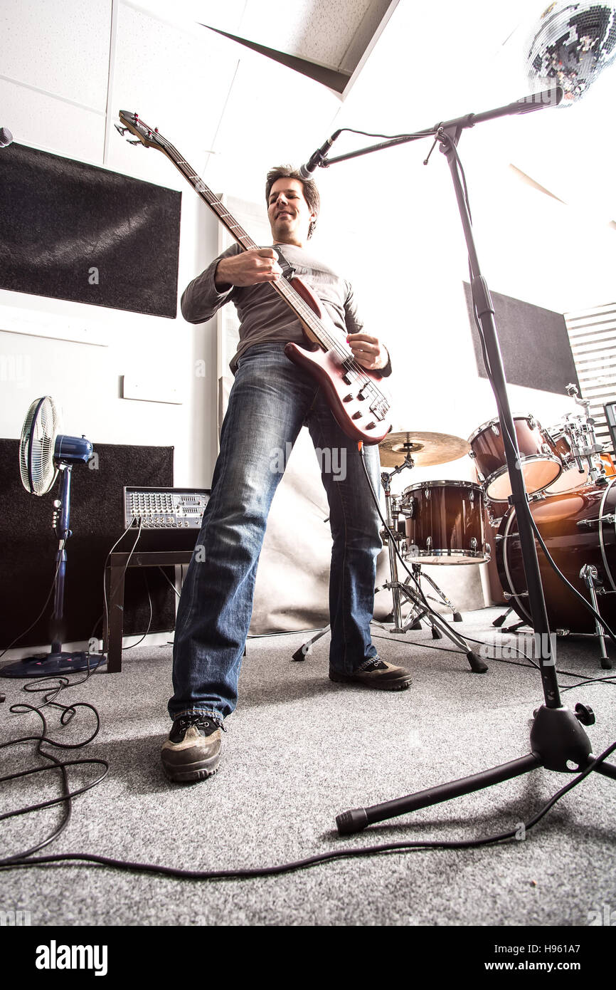 A Rock musician playing passionately bass in the rehearsal Studio Stock ...