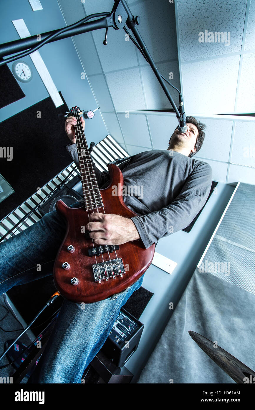 A Rock musician playing passionately bass in the rehearsal Studio Stock ...