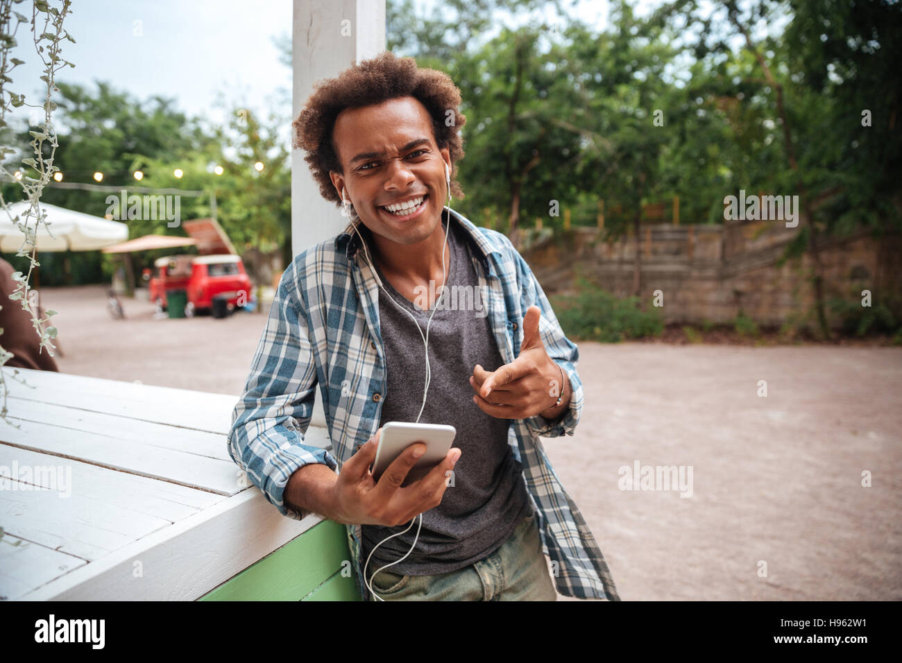 Cheerful african young man listening to music from mobile phone and ...