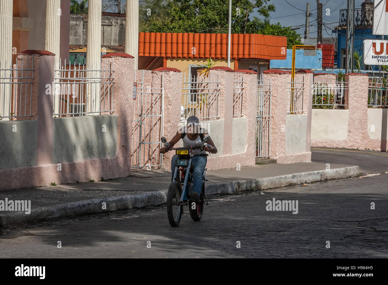 Ordinary young man riding a motorcycle on a street in a typical town in ...