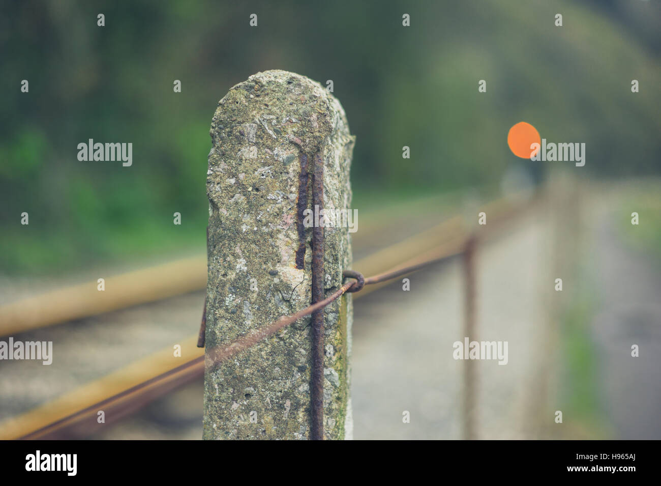 A concrete post forming part of a fence by the railway tracks in the ...