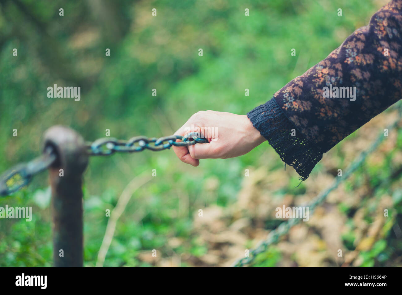 A young female hand is grabbing and holding a railing in the forest ...