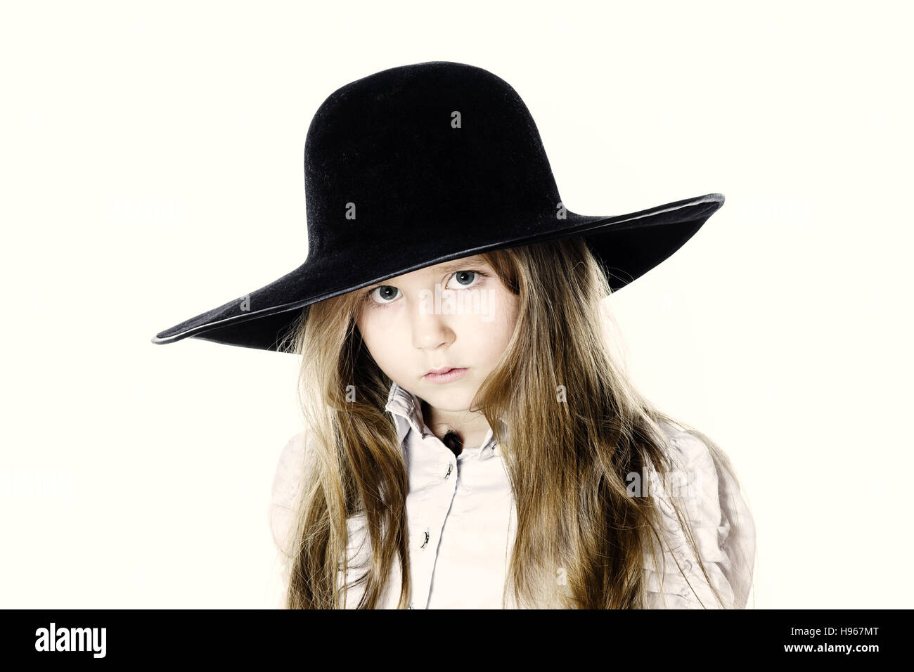 LIttle girl posing like a model in mother's hat, isolated on white ...