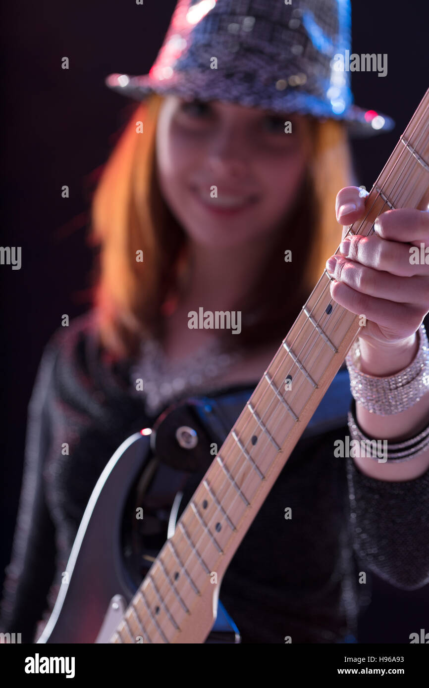focus on the left hand on the guitar grip by a popstar playing her ...