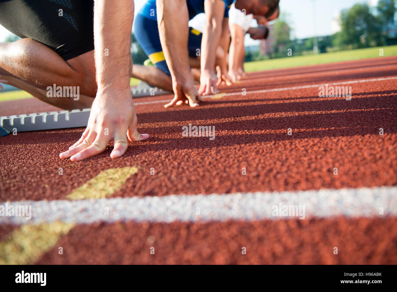 Close-up side view of cropped people ready to race on track field Stock ...