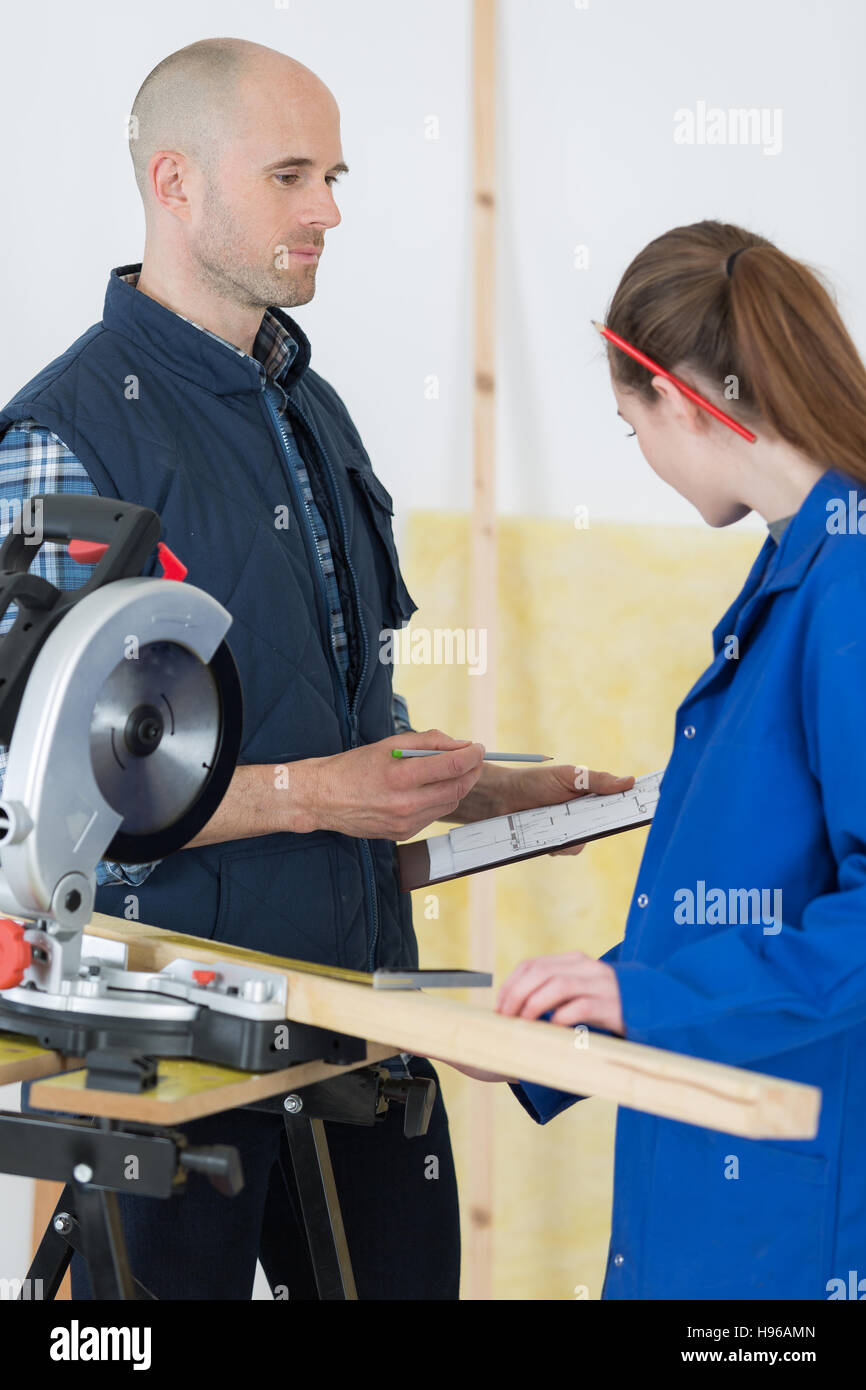 carpentry teacher showing sawing machine to a female student Stock ...
