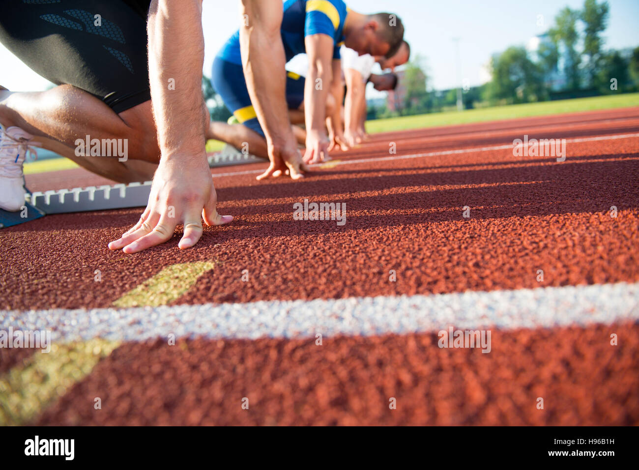 Close-up side view of cropped people ready to race on track field Stock ...
